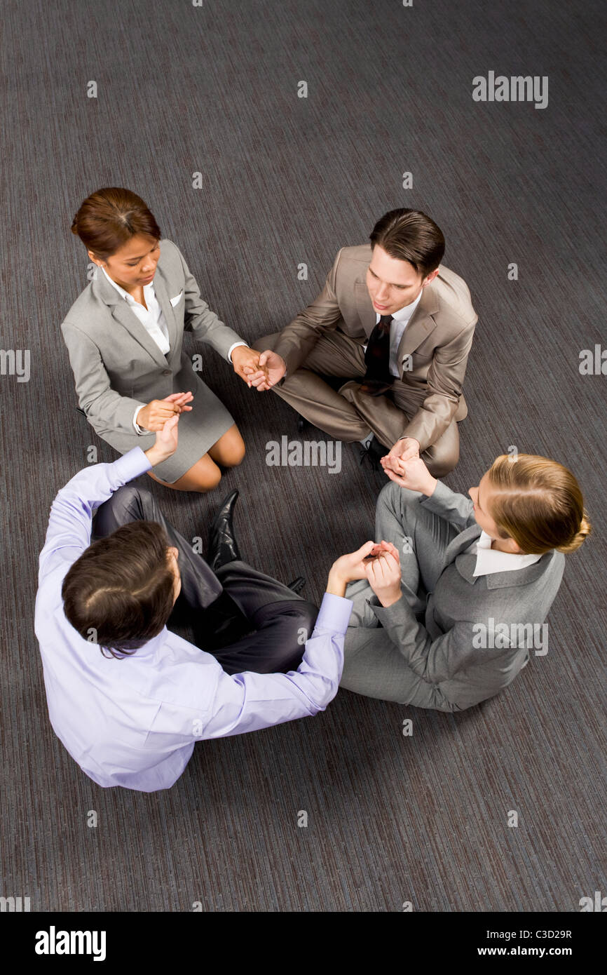 Above view of business people sitting on the floor and holding each ...