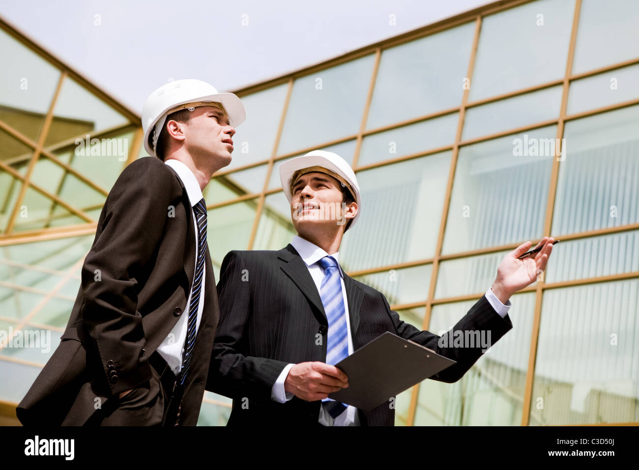 Photo of two co-workers discussing new project with modern building at ...
