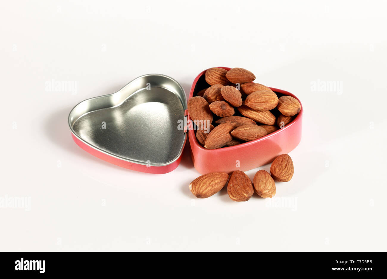 Raw almonds as a heart food indicated by heart shaped tin Stock Photo ...