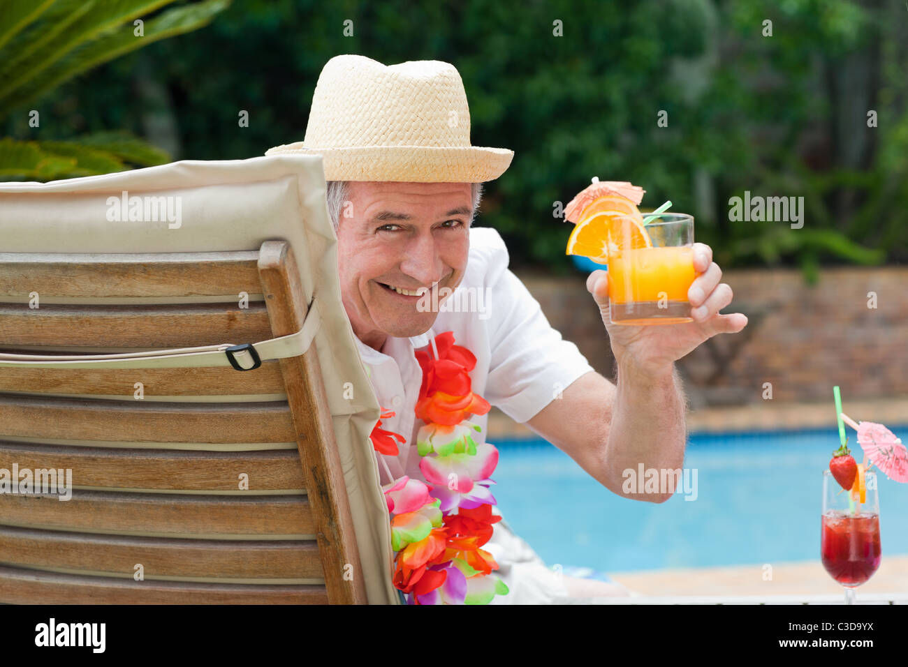 Mature man drinking a cocktail beside the swimming pool Stock Photo - Alamy