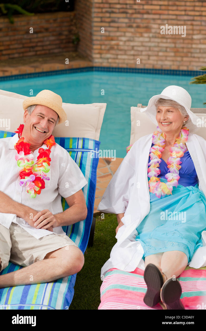 Senior couple lying down beside the swimming pool Stock Photo - Alamy