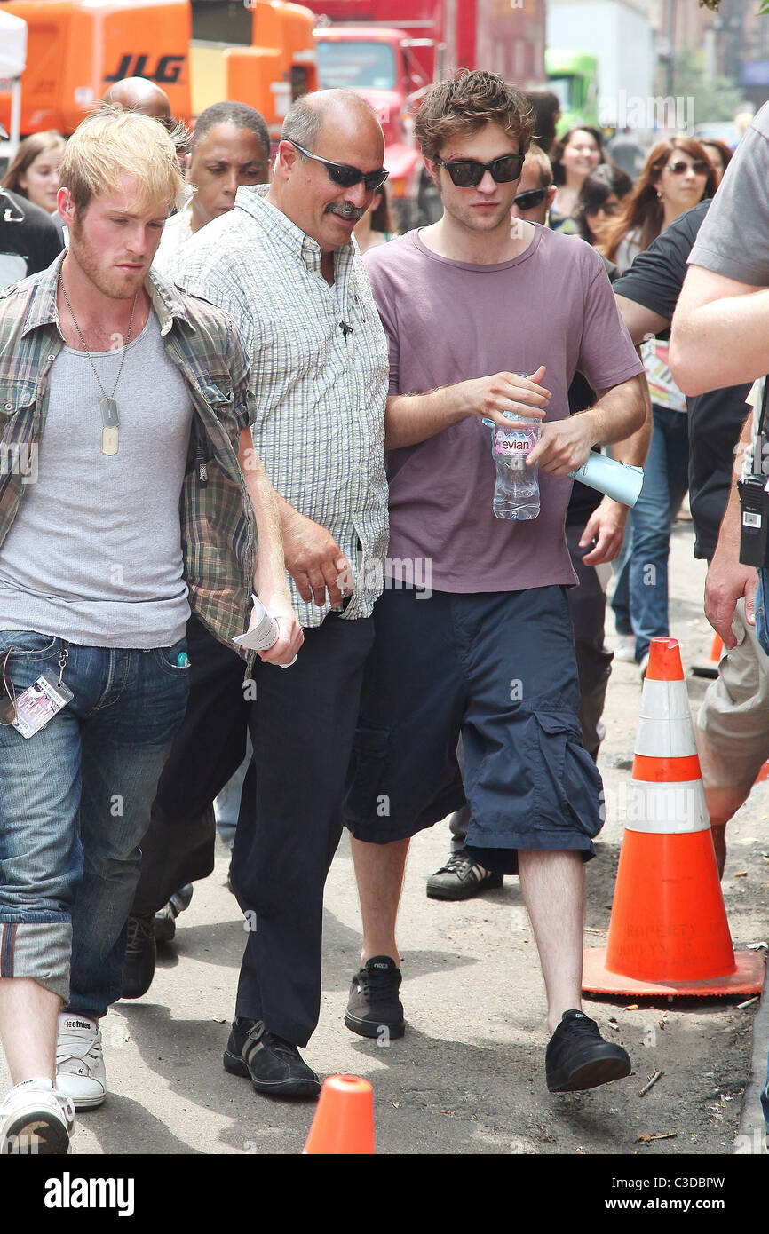 Robert Pattinson is escorted by bodyguards during a break from filming ...