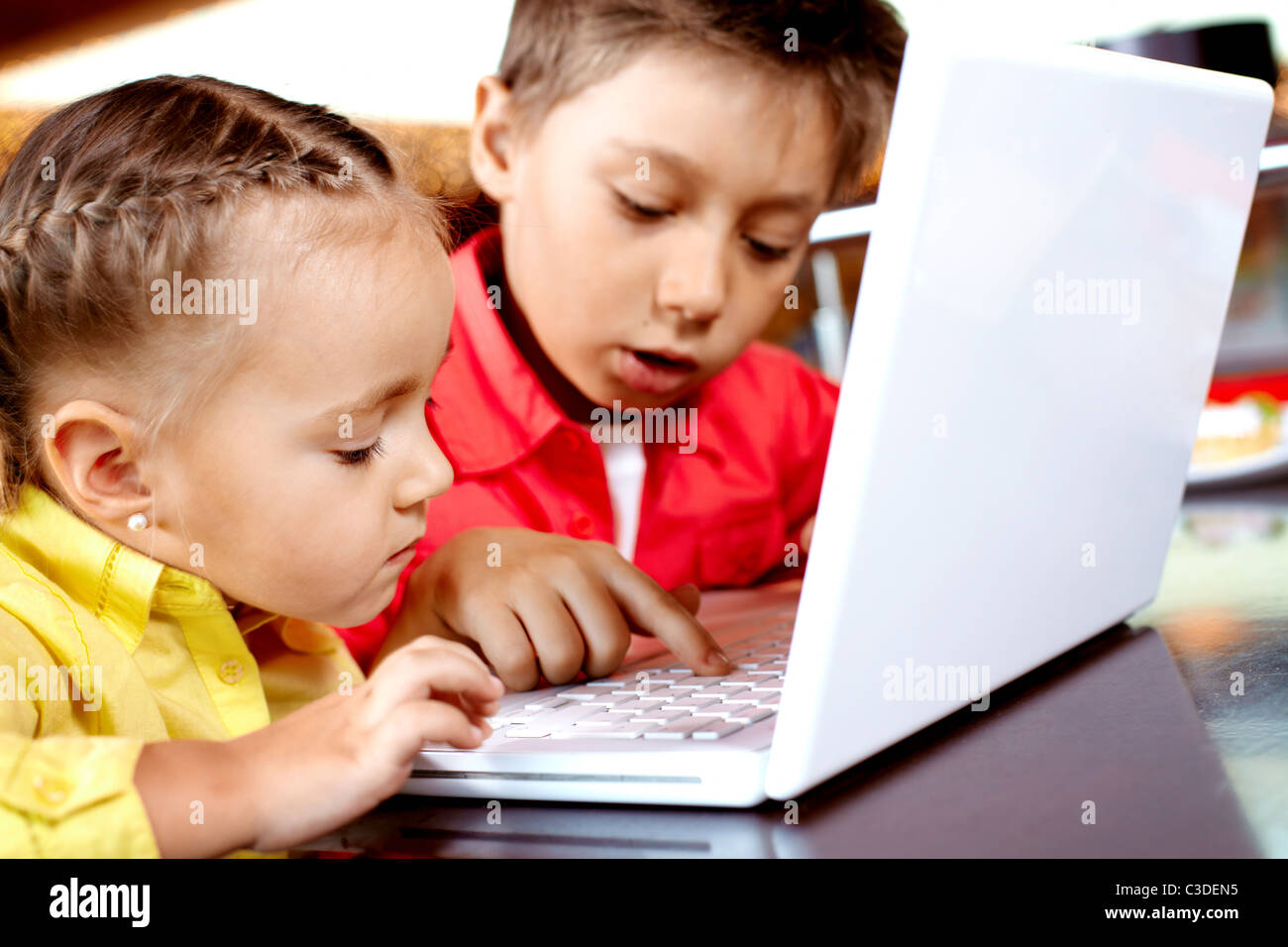 Portrait of cute children typing on laptop Stock Photo - Alamy