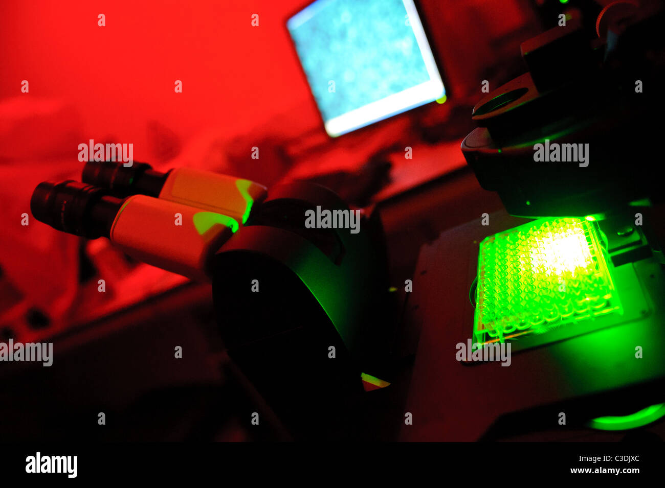 microscope in darkroom lit bright red with computer screen in ...
