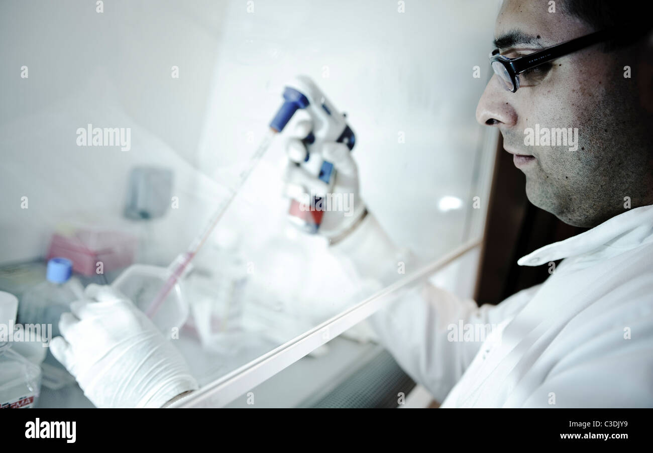 Male scientist white lab coat white gloves and glasses working at fume ...