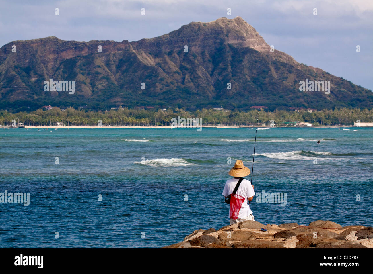 Hawaiian fisherman fishing off rocks at Ala Moana beach park-Waikiki ...