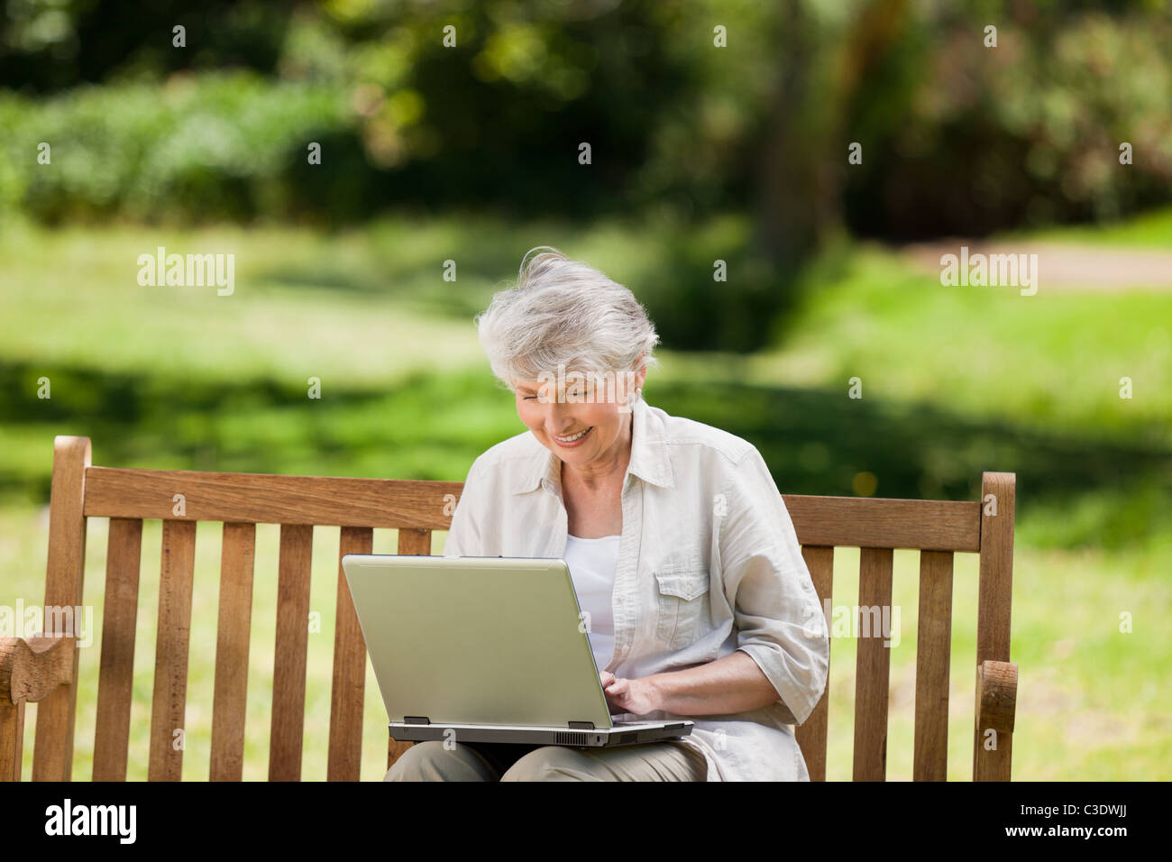 Mature woman working on her laptop on the bench Stock Photo - Alamy