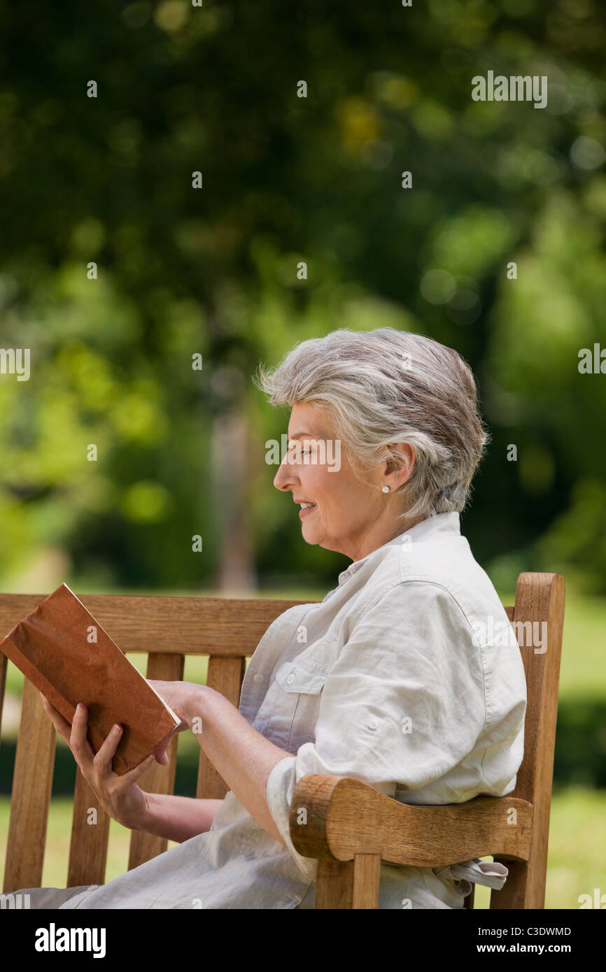 Retired woman reading a book on the bench Stock Photo - Alamy