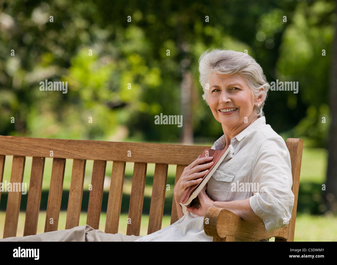 Retired woman reading a book on the bench Stock Photo - Alamy