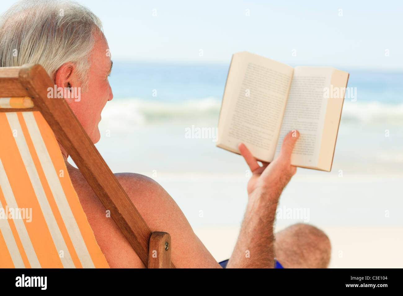 Senior man reading a book at the beach Stock Photo - Alamy