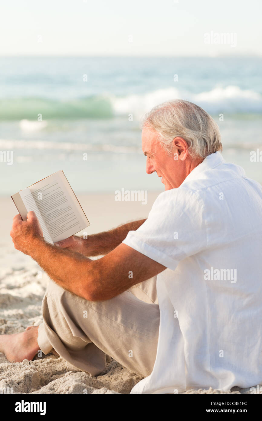 Man reading a book on the beach Stock Photo - Alamy