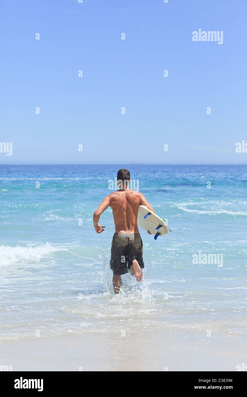 Man running on the beach with his surfboard Stock Photo - Alamy