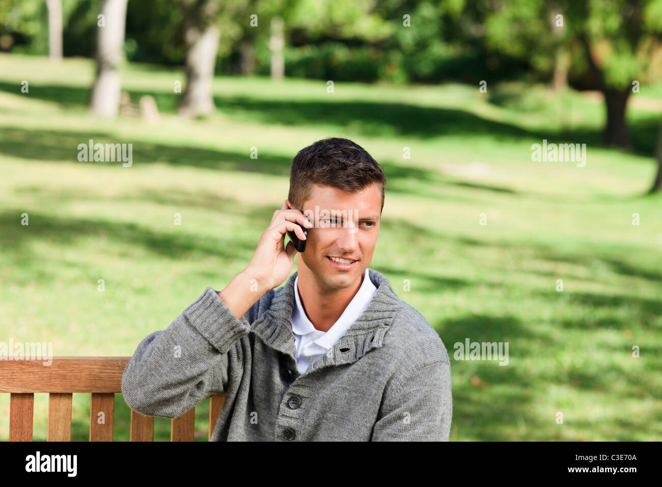 Young man phoning on the bench Stock Photo - Alamy