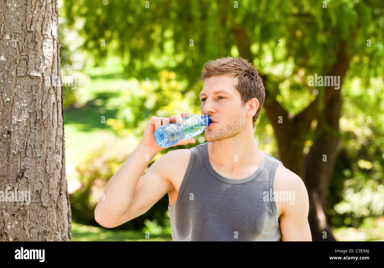 Sporty man drinking water in the park Stock Photo - Alamy