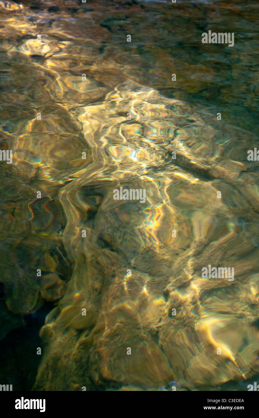 Sun rays light up rocks under the surface of Marshall Lake in western ...
