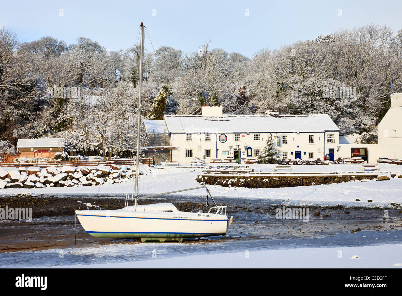 Moored yacht and The Ship Inn pub with snow in winter 2010. Red Wharf ...