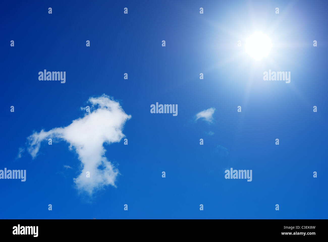Sun shinning in a blue sky beside little white cloud Stock Photo - Alamy