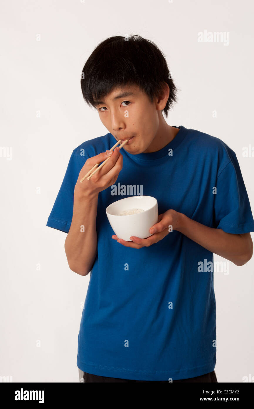 teenage Asian Chinese boy eating rice with chopsticks against white ...
