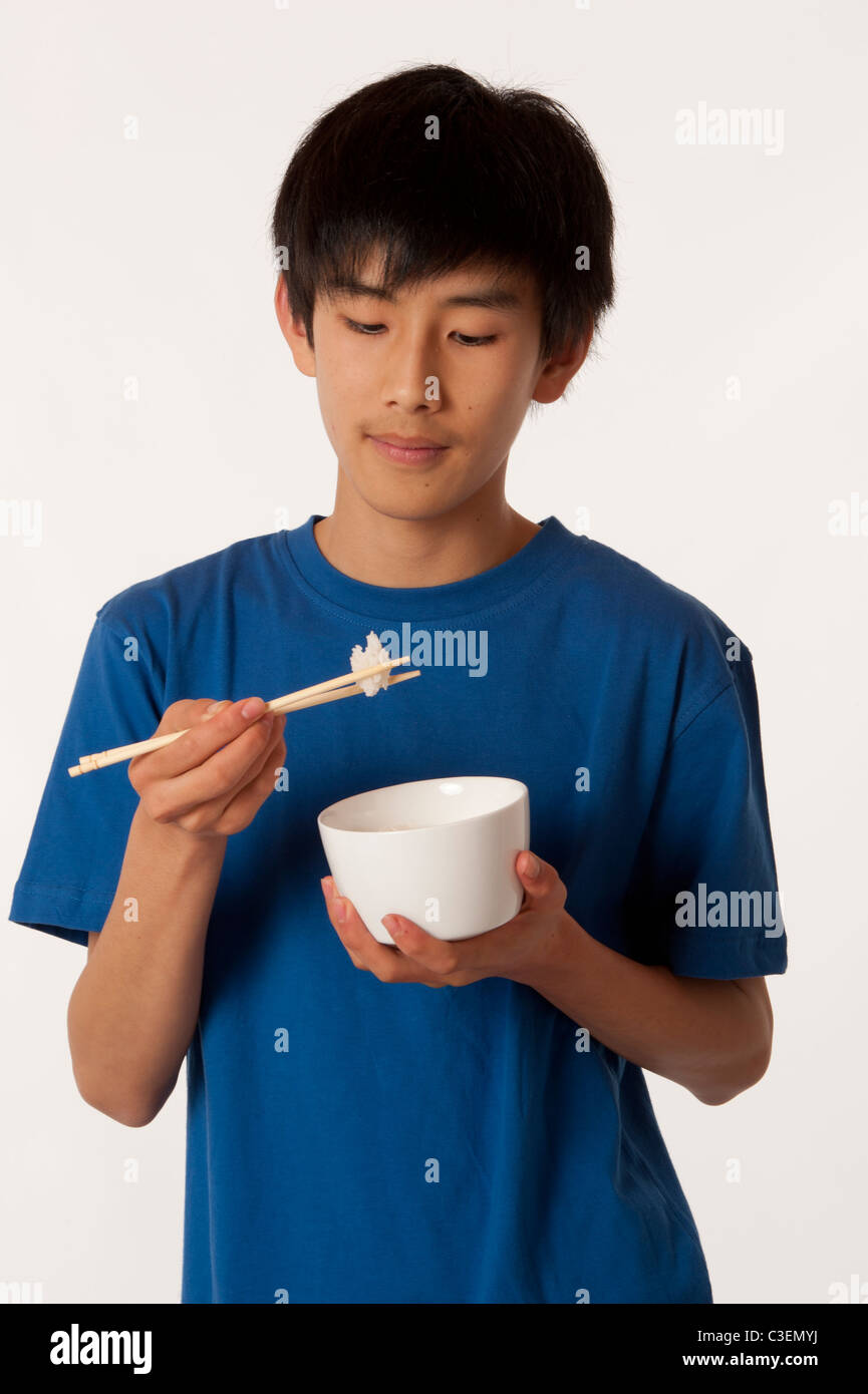 teenage Asian Chinese boy eating rice with chopsticks against white ...