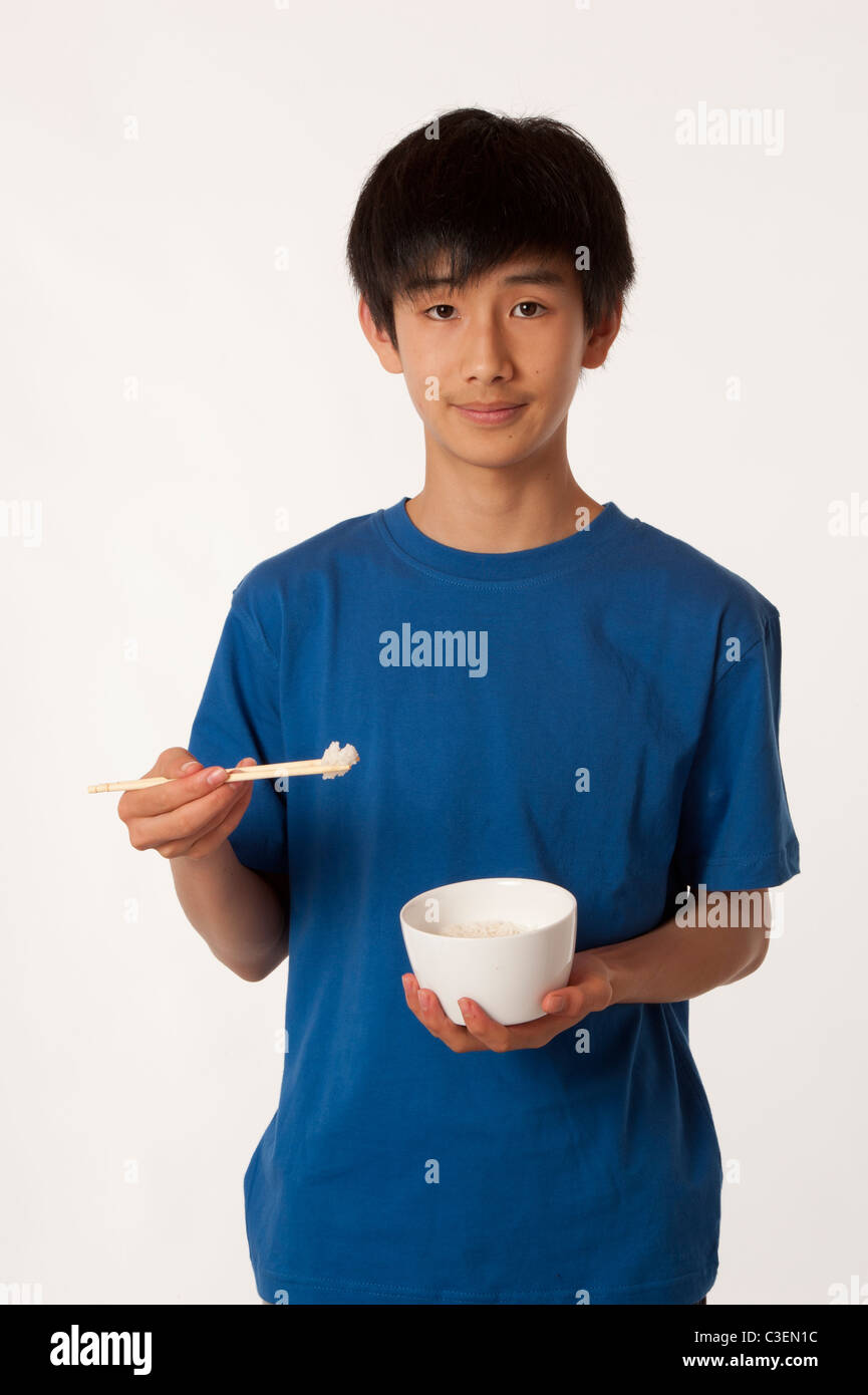 teenage Asian Chinese boy eating rice with chopsticks against white ...