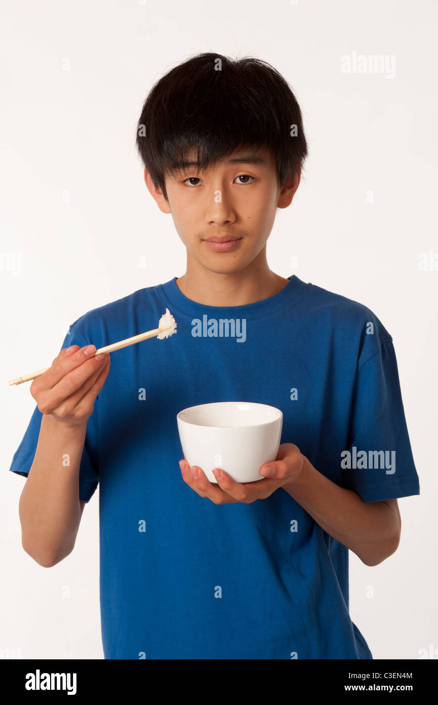 teenage Asian Chinese boy eating rice with chopsticks against white ...