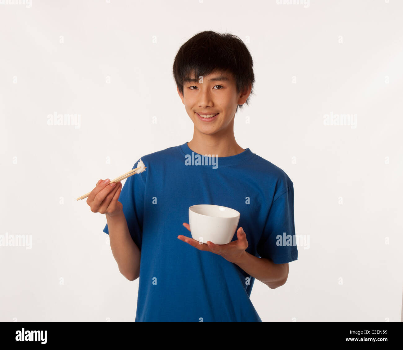 teenage Asian Chinese boy eating rice with chopsticks against white ...