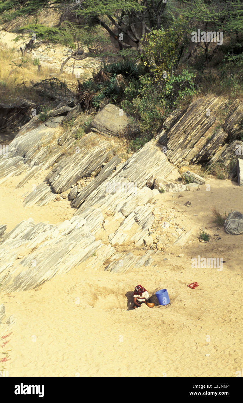 Tanzania. Woman fetching water from a dug hole in a dry river bed in ...