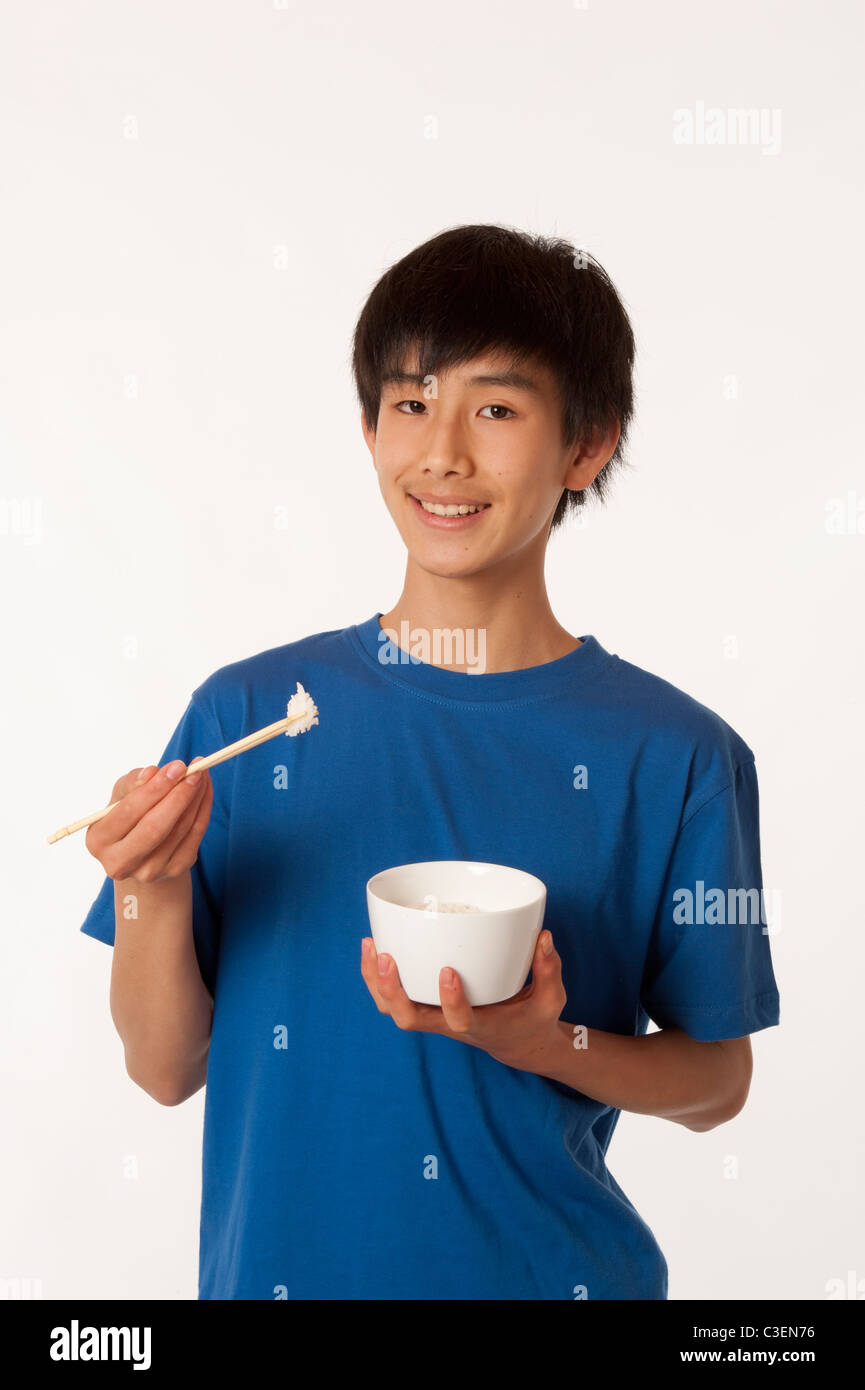 teenage Asian Chinese boy eating rice with chopsticks against white ...