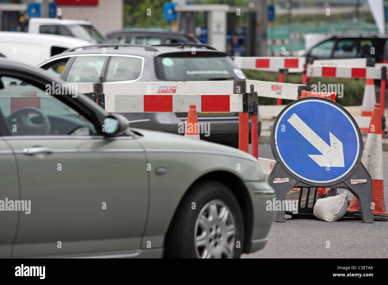 Vehicles passing direction signs and safety barriers around roadworks ...