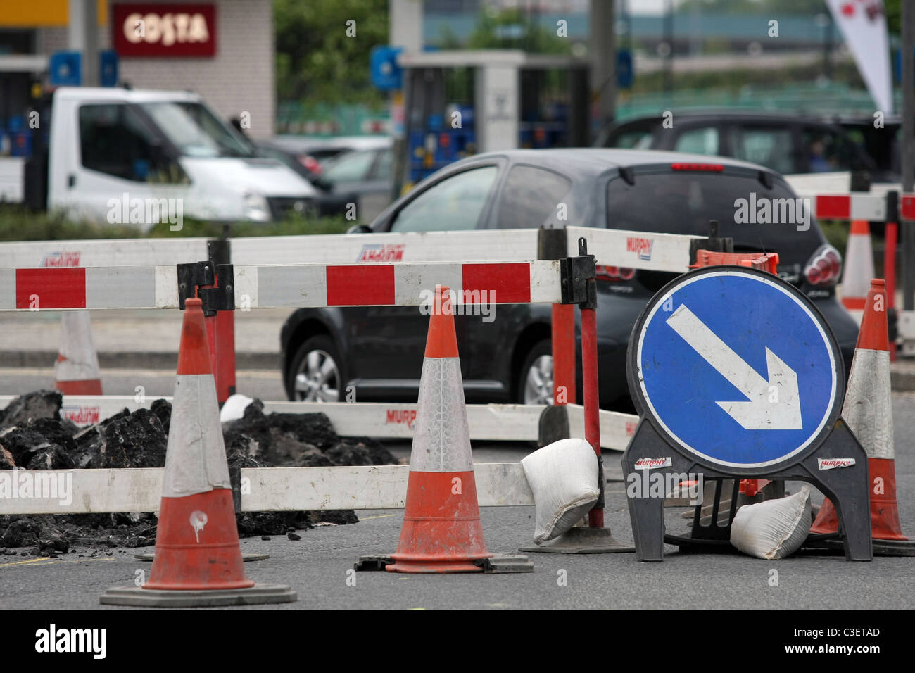 Vehicles passing direction signs and safety barriers around roadworks ...