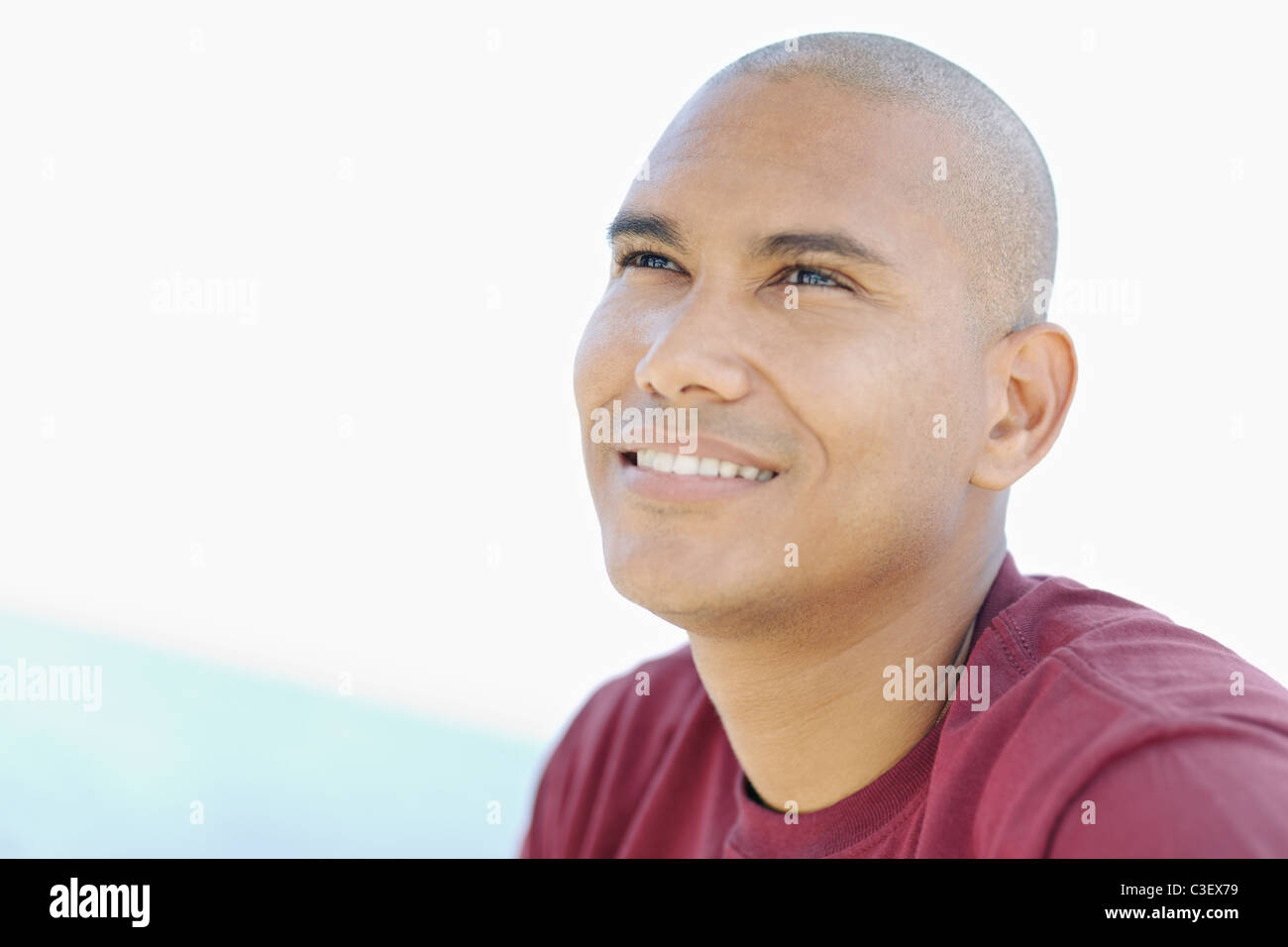 portrait of young hispanic guy with shaved head looking up to the sky ...