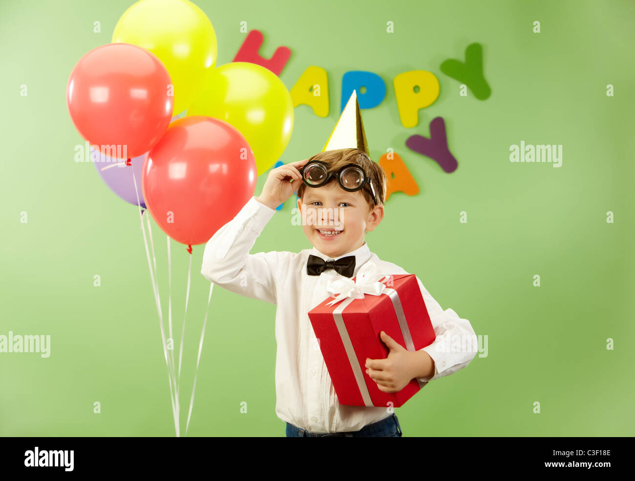 Portrait of happy lad with giftbox putting off funny eyeglasses on ...
