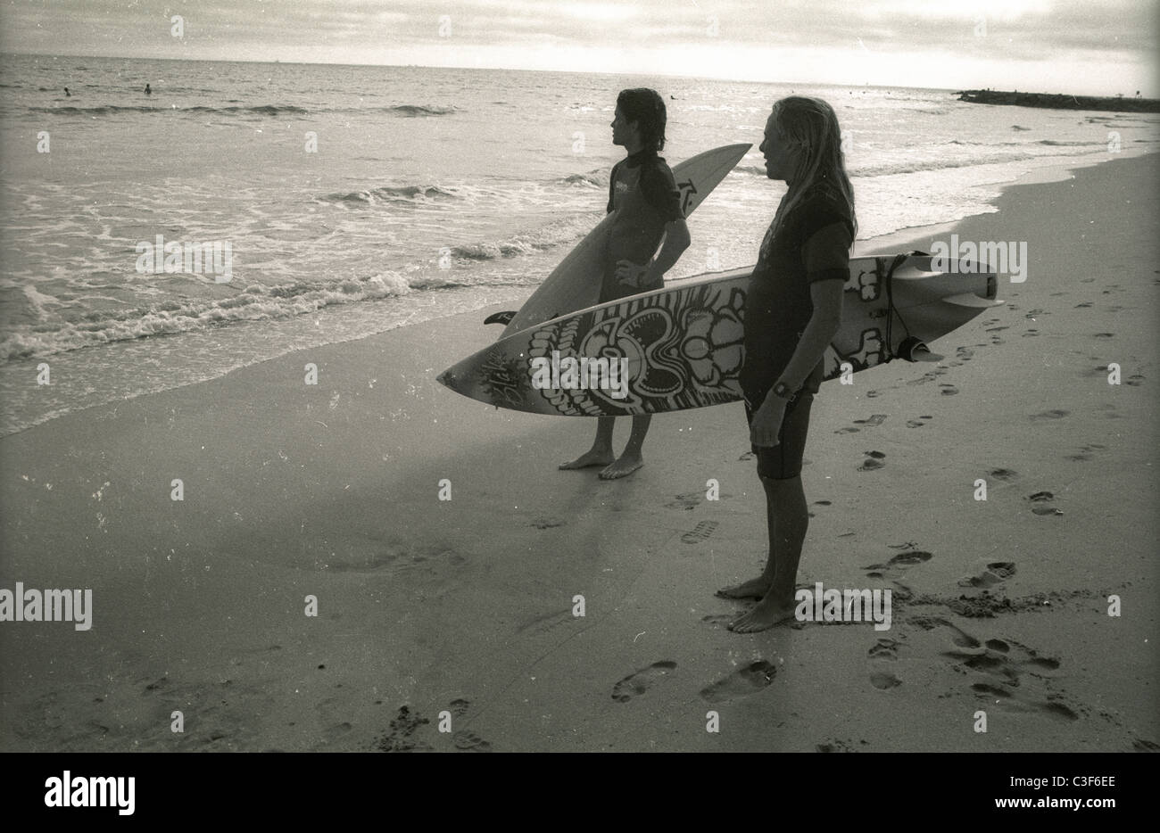 Two surfers on Newport Beach with surfboards at sunset 1991 1990s ...