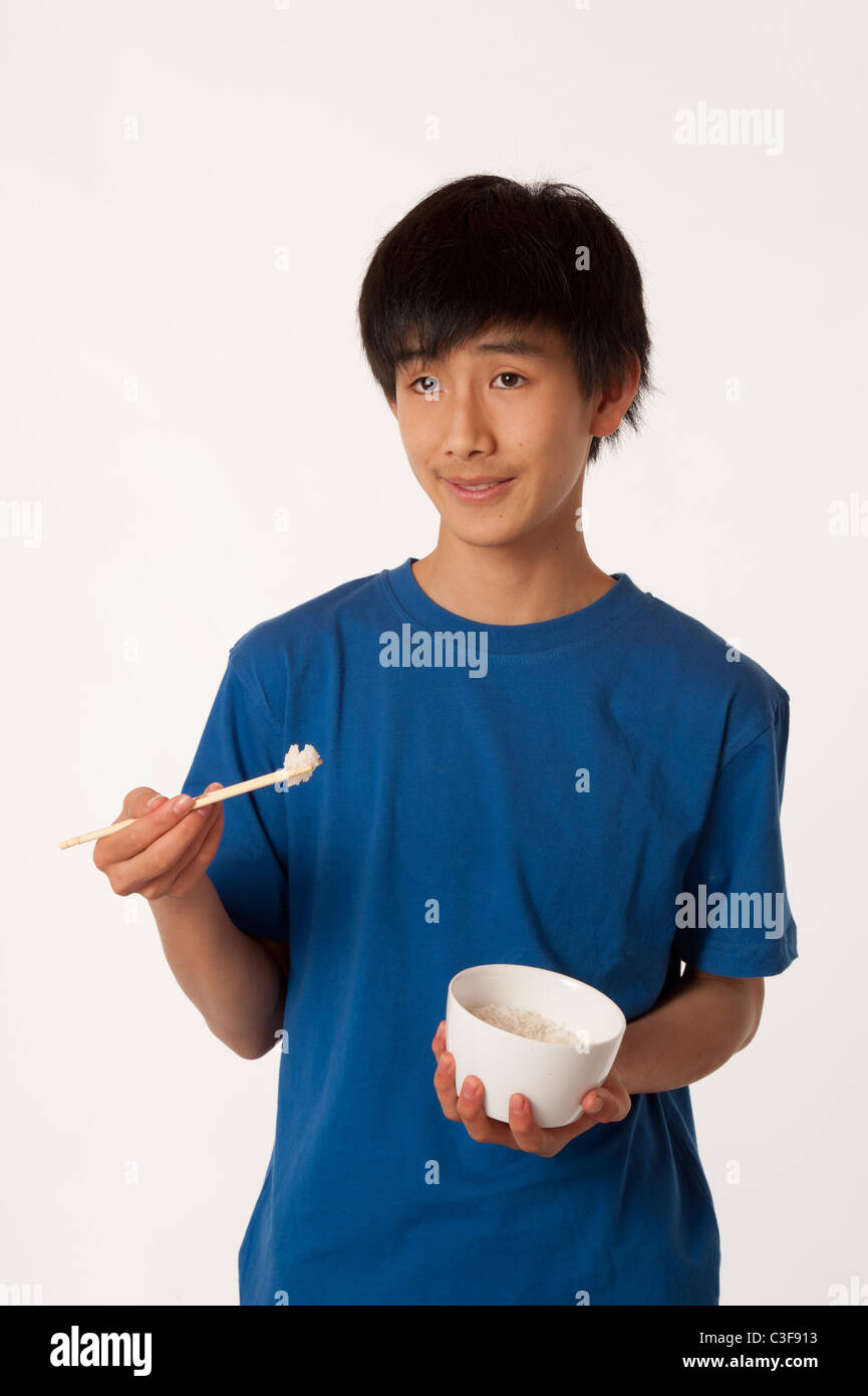 teenage Asian Chinese boy eating rice with chopsticks against white ...