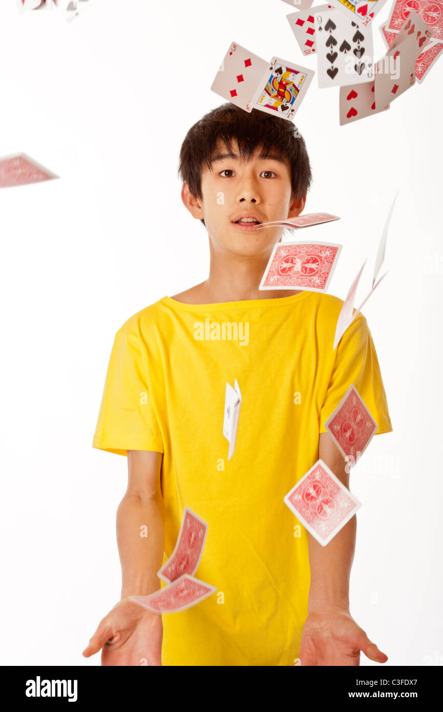 teenage Chinese Asian boy flicking playing cards into the air against ...