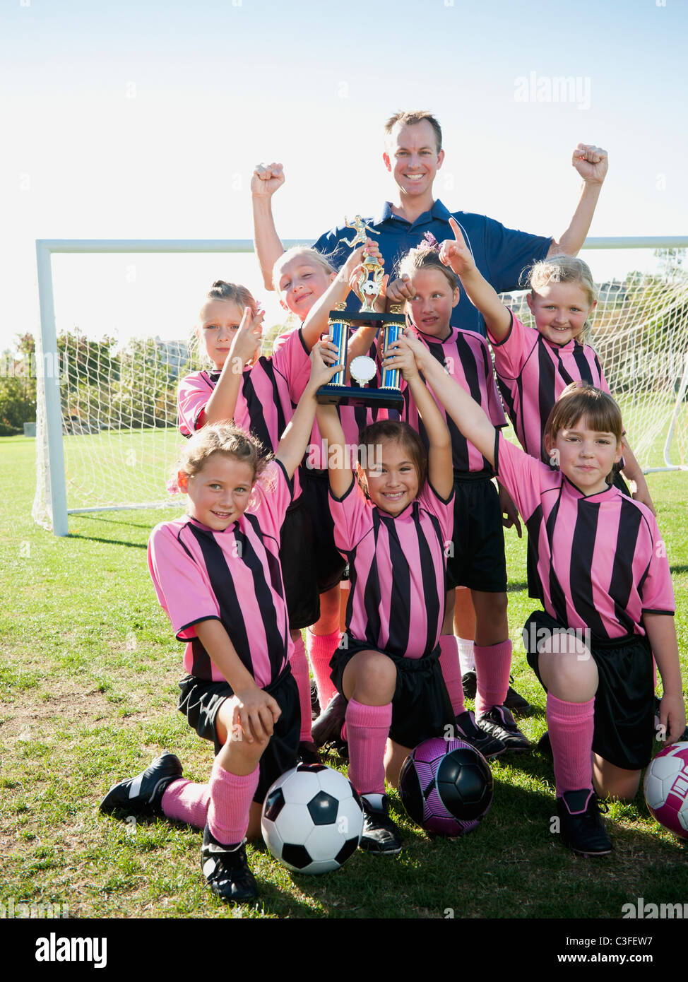 Coach and girl soccer players posing with trophy Stock Photo - Alamy