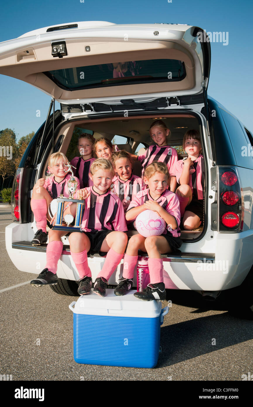 Girl soccer players sitting in back of car with trophy Stock Photo - Alamy