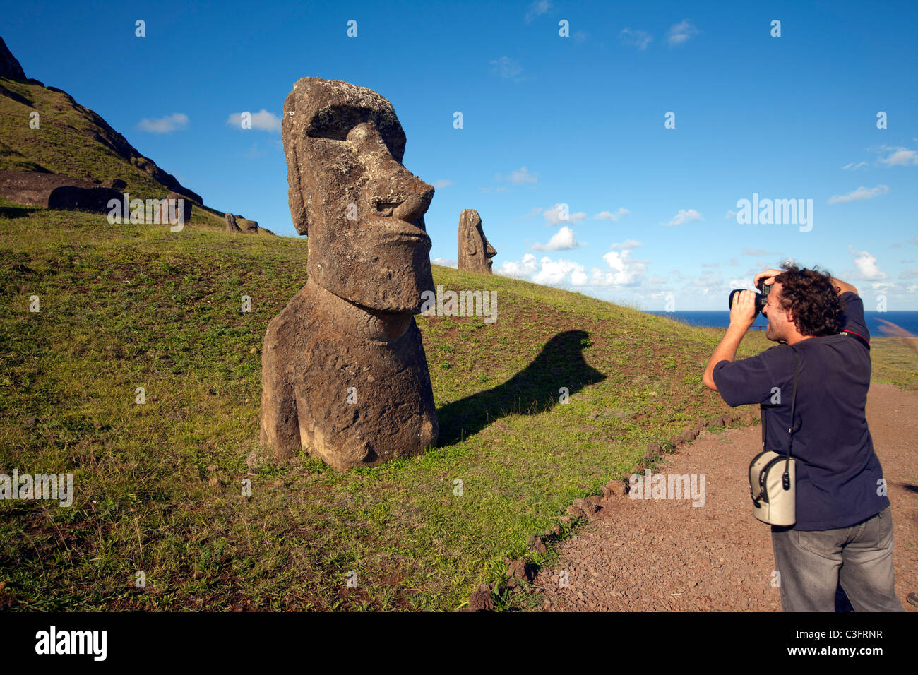 Tourist photographing a Moai on the slopes of Rano Raraku, Easter ...