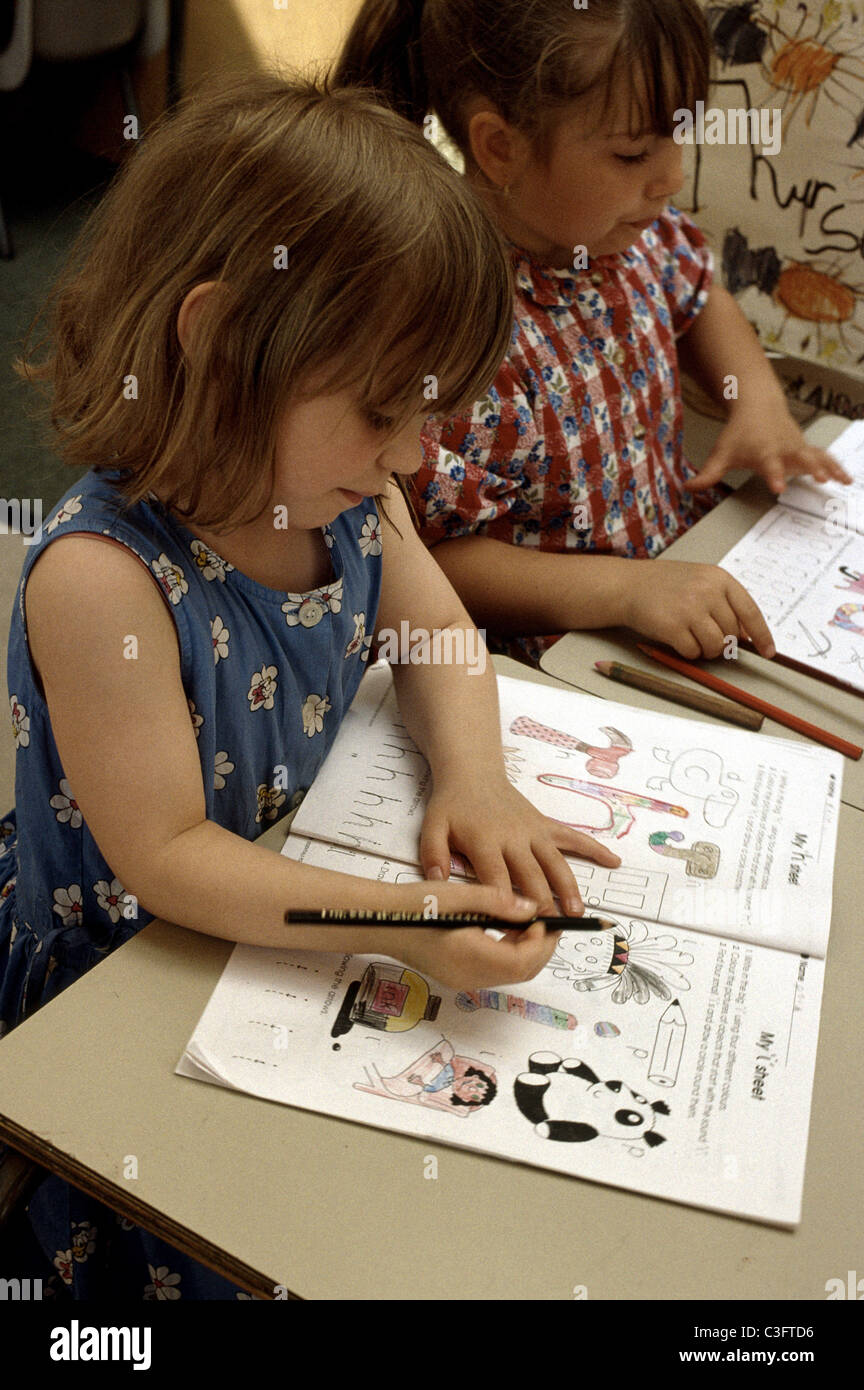 Primary school children writing and reading with their activities book ...