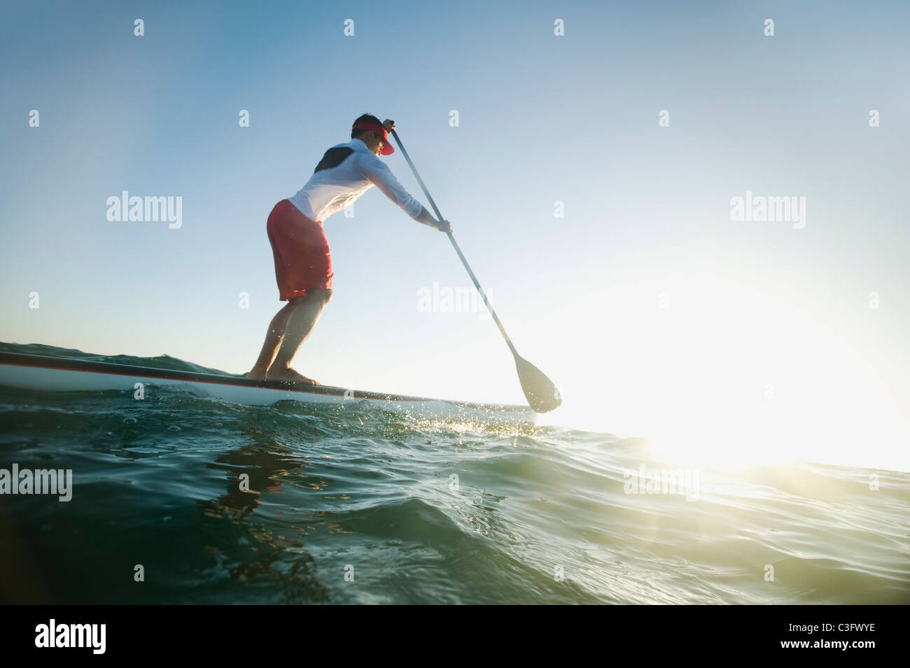 Mixed race man paddling on surfboard Stock Photo - Alamy