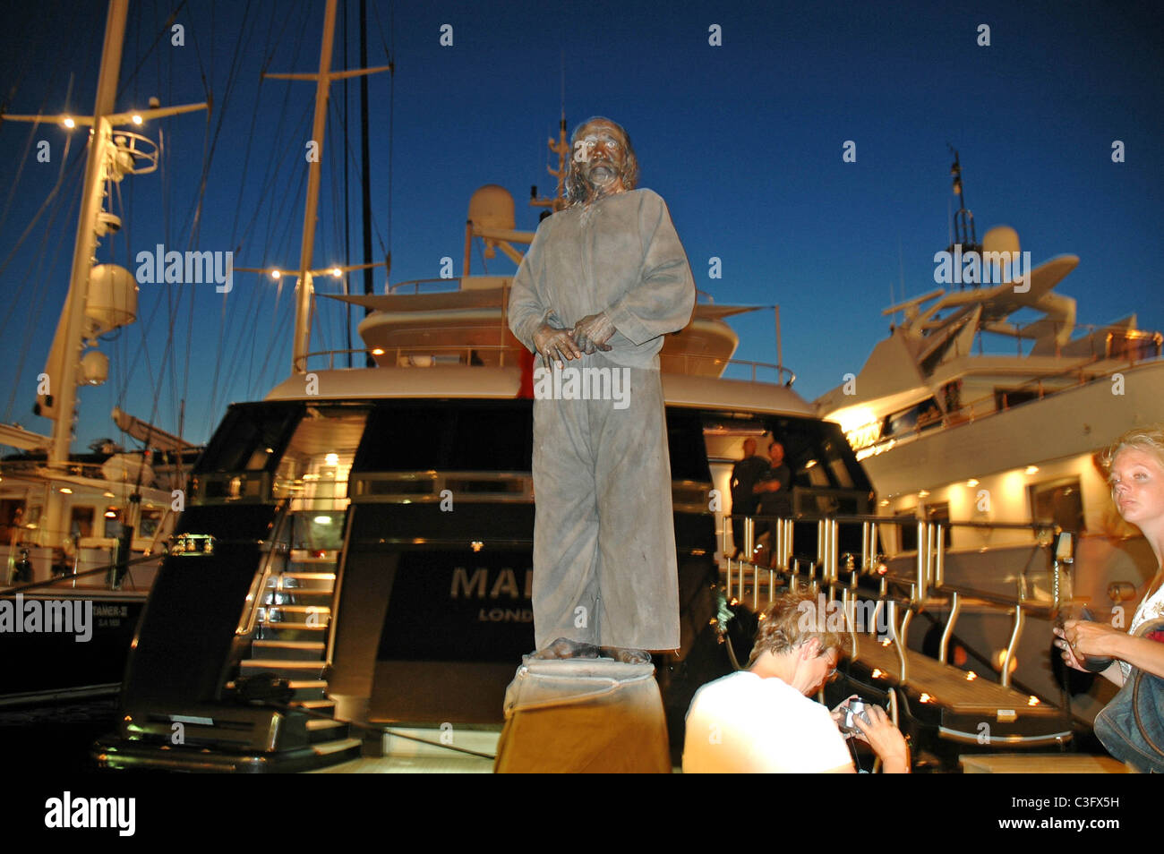 Man acting as a statue in front of luxury boats in the harbour in St ...