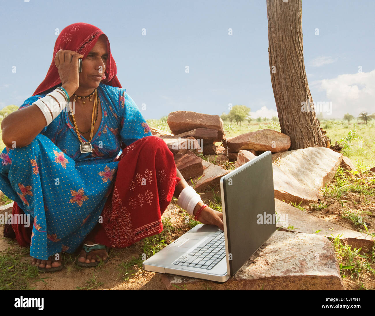 Rural woman talking on a mobile phone and using a laptop, Jaipur ...