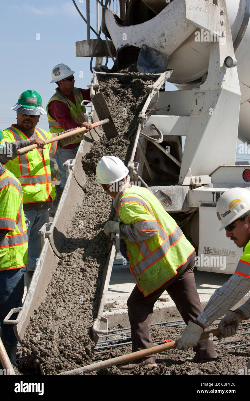 Male highway construction workers pour fresh concrete on stretch of new ...