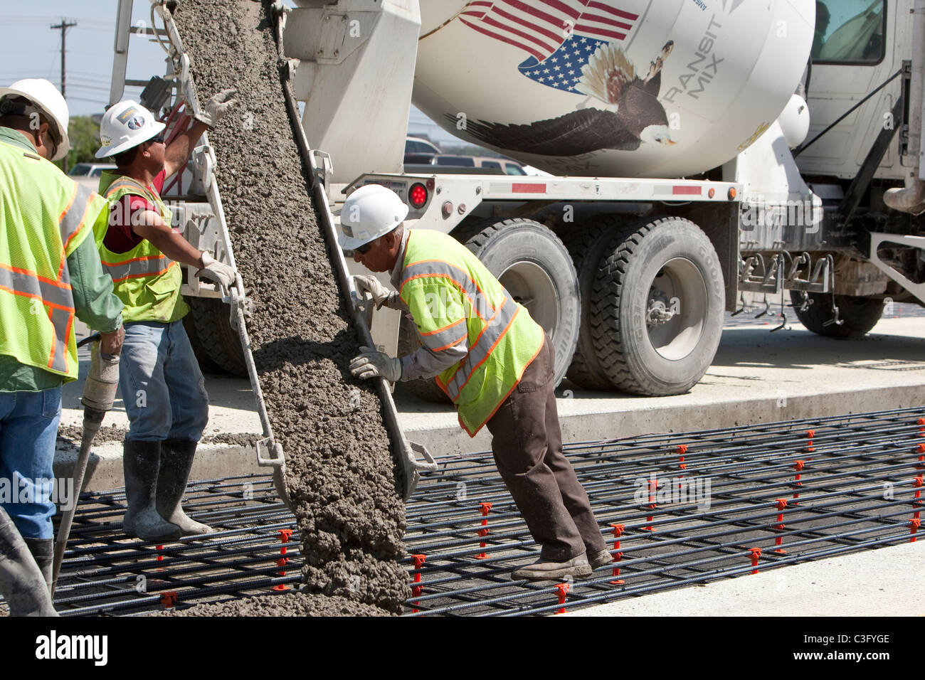 Male highway construction workers pour fresh concrete into beam grid on ...