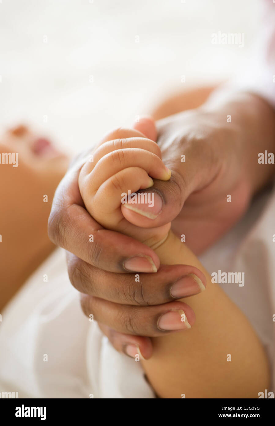 Mixed race woman holding baby's hand Stock Photo - Alamy