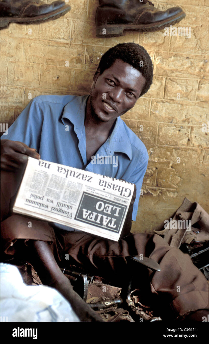 Kenya. Shoemaker reading the Swahilian newspaper Taifa Leo Stock Photo ...