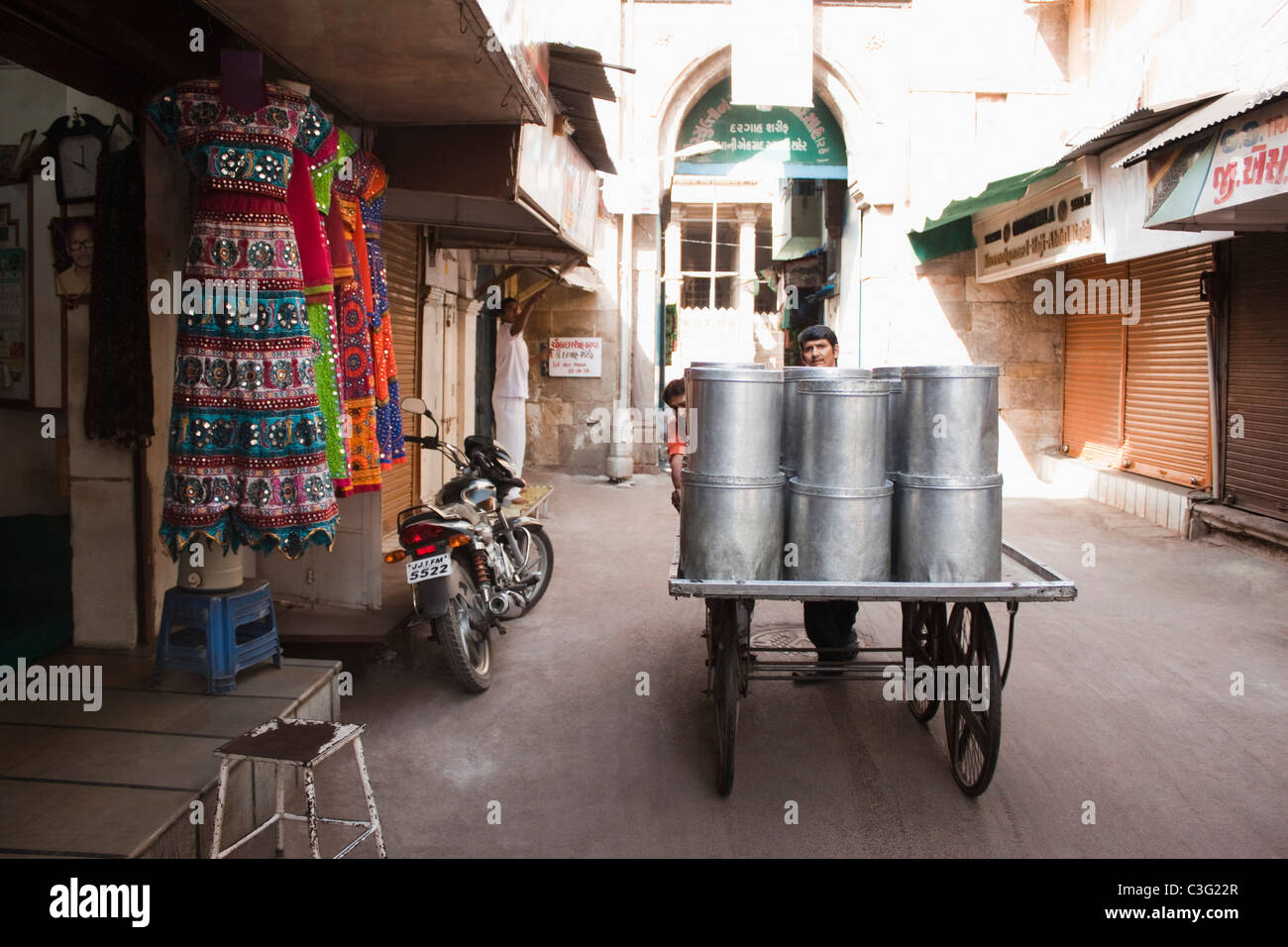 Two men pushing containers on a cart on the street, Ahmedabad, Gujarat ...