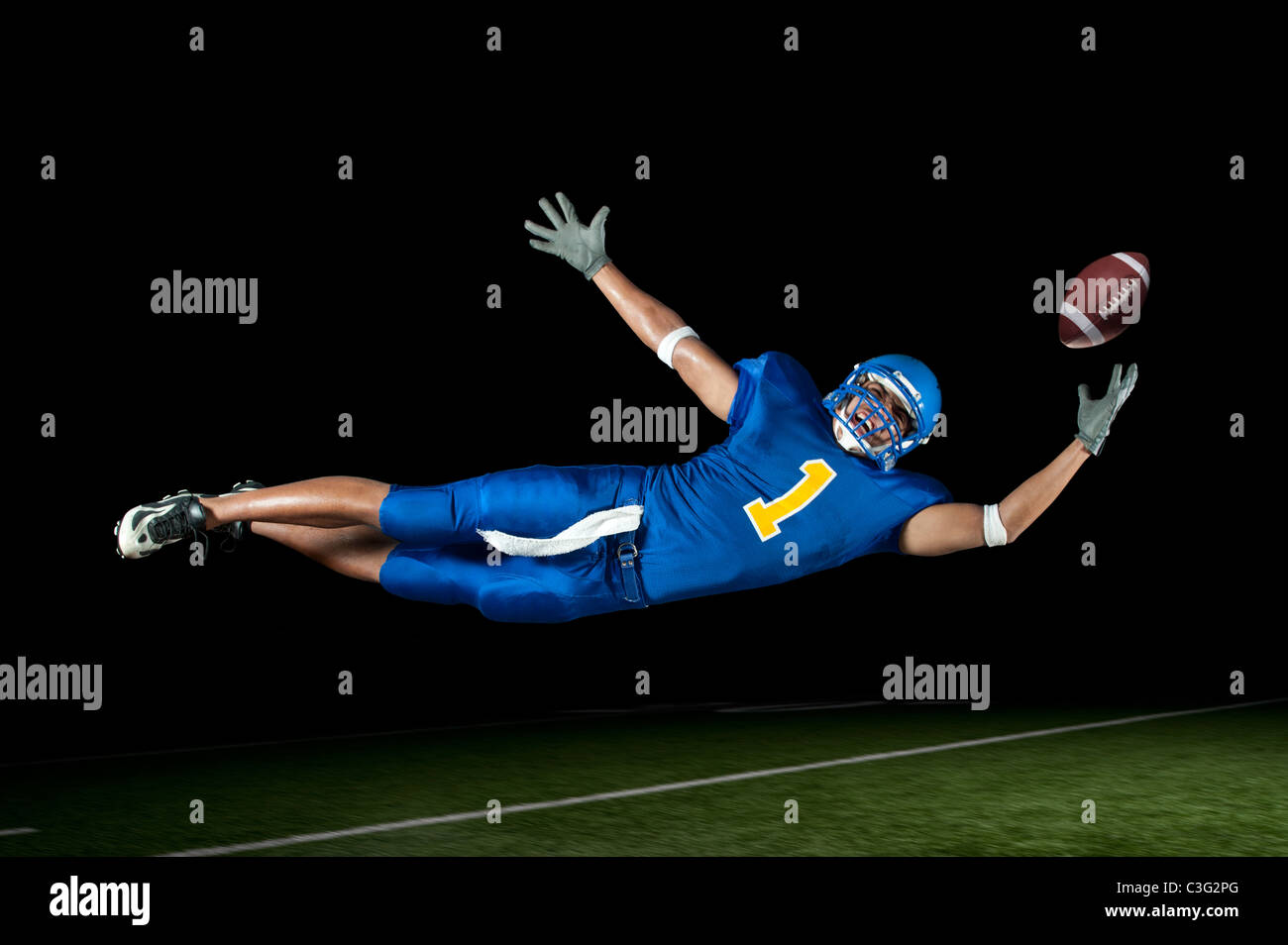 Mixed race football player jumping in mid-air catching football Stock ...