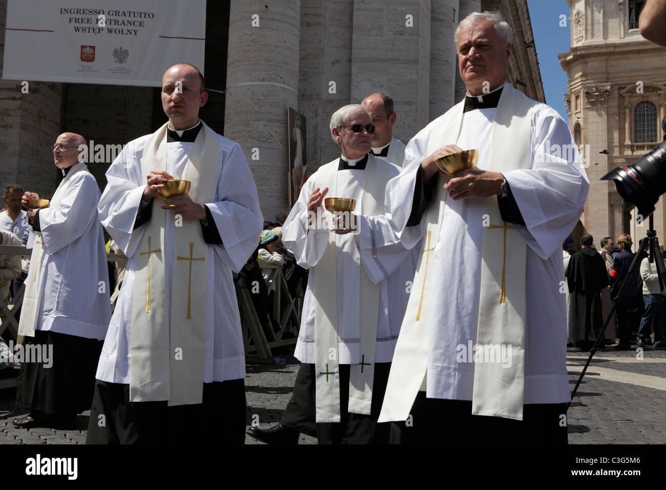 Priests giving out holy communion to faithful in Saint Peter's square ...