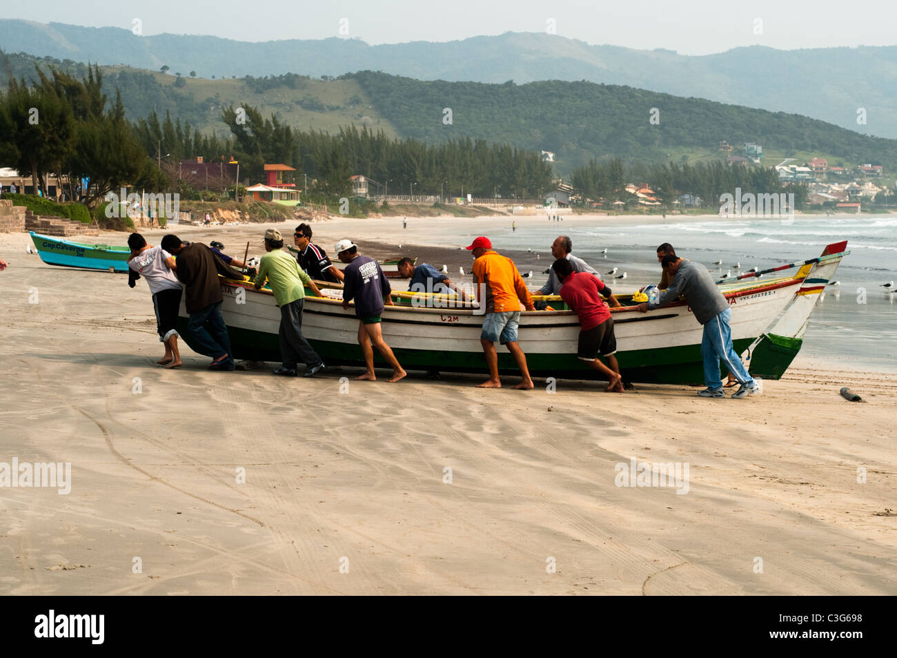 local fisherman pulling their small fishing boat at Garopaba beach ...